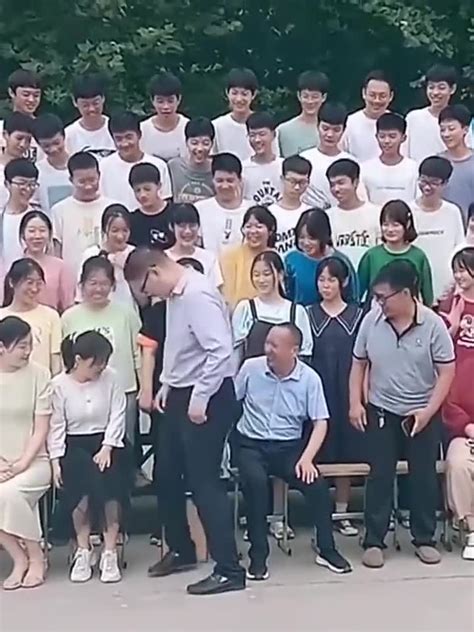 拍毕业照时老师怕挡住后排学生，将椅子放倒后坐下