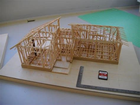 A Model Of A House Being Built On Top Of A Wooden Table Next To A Ruler