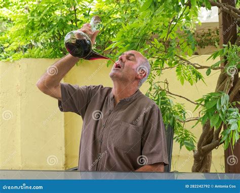 Older Man Sitting At A Table With A Glass Of Red Wine In His Hand Stock