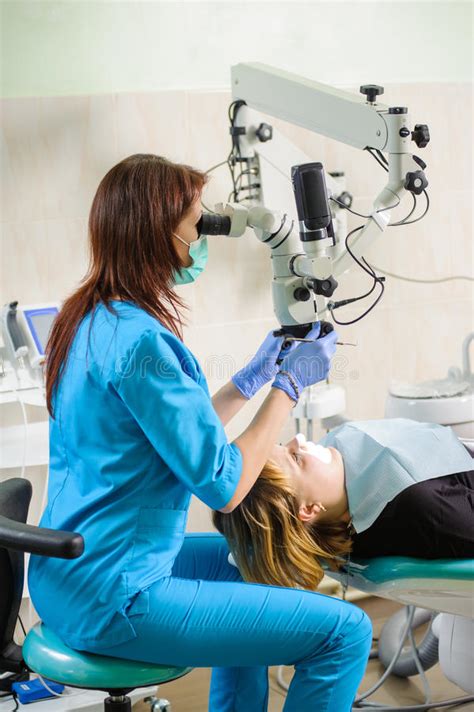 Female Dentist Working With Microscope At Modern Dentist Clinic Stock