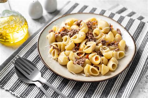 회색 요리 배경에 접시에 비앙코에서 스튜와 파스타 파이프 리게이트 부엌 테이블 클로즈업에 갈은 쇠고기와 전통적인 이탈리아 파스타