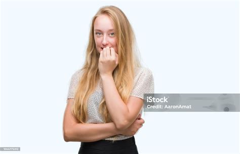 강조 하 고 손톱을 물어 뜯고 입에 손을 긴장을 찾고 두더지 셔츠를 입고 금발 십 대 여자 불안 문제입니다 감정에 대한 스톡