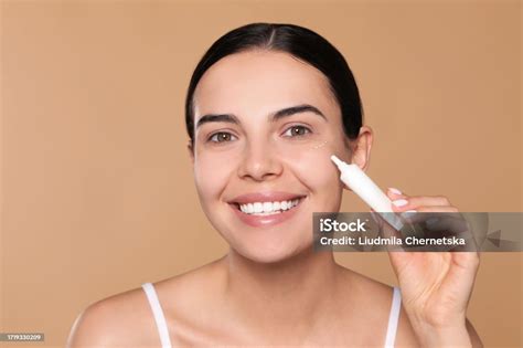 ベージュの背景に目の下の皮膚にゲルを塗る美しい若い女性 美しい女性のストックフォトや画像を多数ご用意 美しい女性 1人 25 29