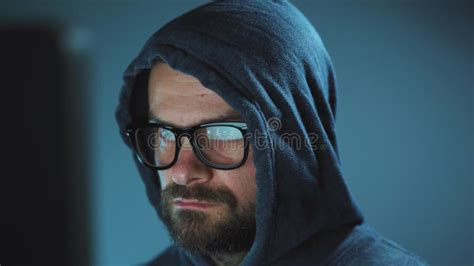 Male Hacker In The Hood And Glasses Working On A Computer In A Dark