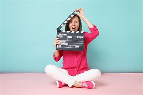 전체 길이 총된 여자 장미 셔츠 화이트에서 바지 만들기 Clapperboard 밝은 핑크 블루 파스텔 벽 배경 스튜디오에 절연