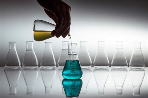 과학 실험실 유리 에렌마이어 플라스크에서 파란색 액체에 노란색을 붓는 손은 반사 표면에 유리 제품 장비와 함께 Stem 주제에 대한 스톡 사진 및 기타 이미지 Istock