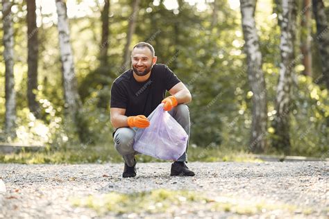 Homem Recolhe Lixo Em Sacos De Lixo No Parque Foto Grátis