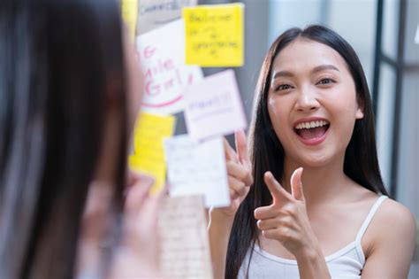 캐주얼 휴식 젊은 성인 여성 아시아 여성은 심호흡을하기 전에 거울에 자신을 응원하고 인생 인용문 동기 부여와 함께 종이 노트로 가득 찬 거울 앞을 들여다 보며 아름다운