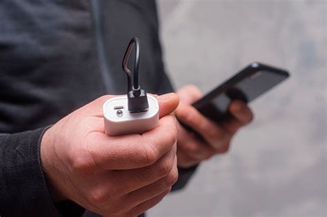 남자는 손에 보조 배터리를 들고 콘크리트 벽에 스마트 폰을 충전합니다 개인 장식품에 대한 스톡 사진 및 기타 이미지 개인