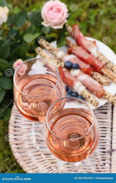 Glasses Of Delicious Rose Wine And Food On Picnic Basket Outdoors