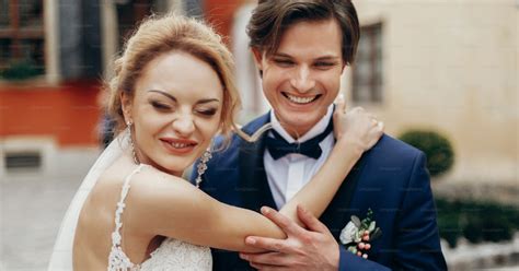 세련된 신부와 신랑은 도시 거리에서 춤을 추고 포옹합니다 행복한 럭셔리 웨딩 커플은 빛 속에서 오래된 건물에서 포옹합니다 낭만적 인 관능적 인 순간 여자와 남자 웃고