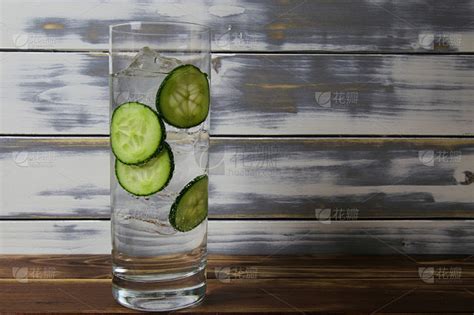 靠近孤立的鸡尾酒杯与金汤力黄瓜片和冰块。木制的老式木板与复制空间背景。