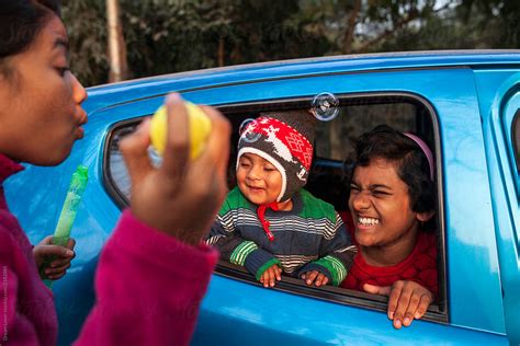 Mother And Daughters Sitting Inside Car And Making Fun With Bubbles