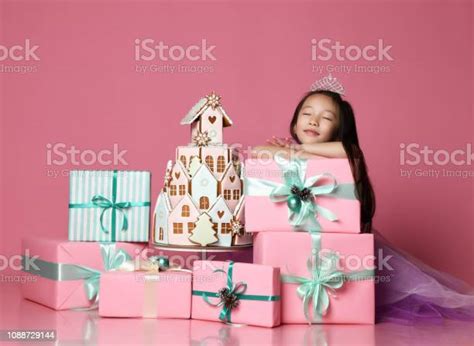 작은 아시아 여 자가 왕관과 보라색 드레스에 많은 선물 상자를 표시 하 고 생강 쿠키 케이크 생일 축 하 귀여운에 대한 스톡