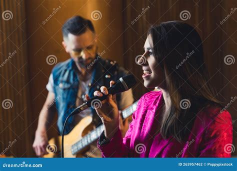 Side View Of A Young Dark Haired Girl Singing Into A Microphone And A
