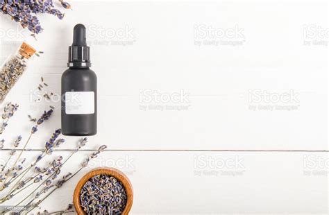 흰색 나무 배경에 라벤더로 만든 화장품이있는 피펫이있는 검은 무광택 병 상단보기 공간의 복사본입니다 브랜드가 없습니다 모스크 업