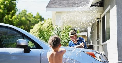 Foto Un Niño Salpica Agua En El Coche De Su Padre Verano Imagen En