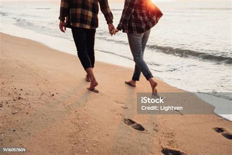 바다에서 일출을 만나는 알아볼 수없는 커플 해안선을 따라 걷는 손으로 잡고있는 남자와 여자 2명에 대한 스톡 사진 및 기타