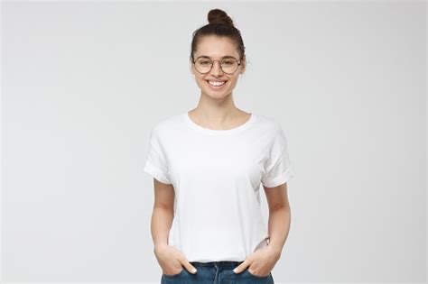 젊은 유럽 여자 주머니에 손을 함께 서 있는 귀하의 로고 또는 텍스트를 회색 배경에 고립에 대 한 복사 공간을 가진 빈 흰색