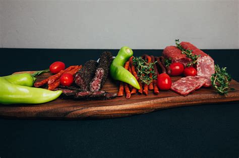 녹색 종이와 토마토가 든 나무 쟁반에 다양한 종류와 크기의 소시지 어두운 배경에 훈제 소시지 세트 가공육에 대한 스톡 사진 및 기타 이미지 Istock