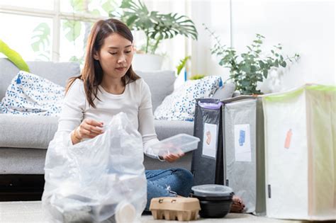 아시아의 젊은 여성이 집에 앉아 종이와 플라스틱 쓰레기를 분리하고 있다 재활용을 위한 쓰레기 분류 지구 온난화 감소 환경 보호의