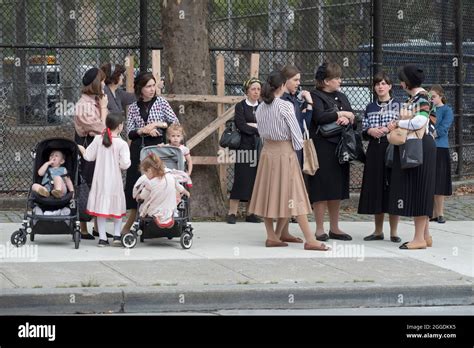 A Group Of Modestly Dressed Orthodox Jewish Mothers And Families Wait For A School Bus To Arrive