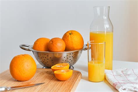 밝은 아침을 위해 테이블에 신선한 천연 오렌지 주스 유리 나무 판에 신선한 주스를 만들기 위한 얇게 썬 육즙 오렌지 아침 식사에 대 한 비타민 음료 건강한 라이프스타일 천연