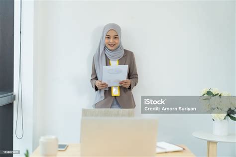히잡 머리 스카프를 입은 아시아 무슬림 사업가가 현대 사무실에서 종이 차트와 함께 일하고 있습니다 비즈니스 인력 다양성 및