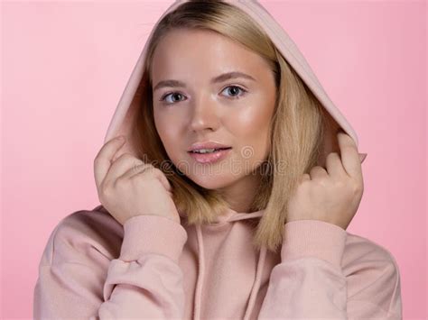 Una Guapa Rubia Joven Con Una Capucha Rosa Le Pone Una Capucha En La Cabeza Imagen De Archivo