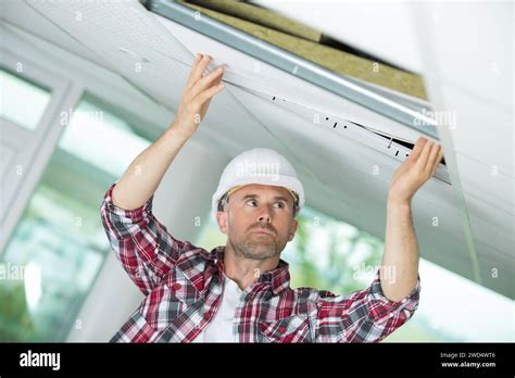 Man In Builder Uniform Hand Up Installing Suspended Ceiling Stock Photo