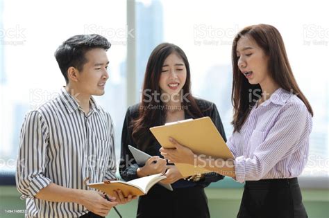 젊은 아시아 사업가 팀이 함께 토론하고 연구하고 브레인스토밍하고 현대 사무실 건물과 도시 배경에서 비즈니스 회의에서 작업을