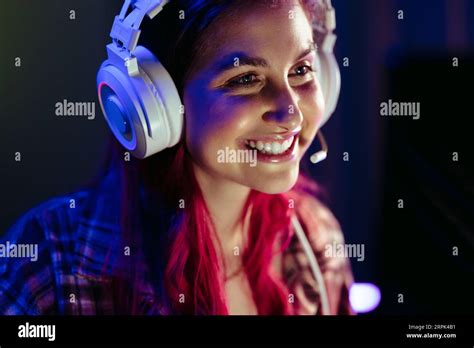 Female Gamer Navigates A Video Game With Headphones On Streaming And Sharing Her Passion With
