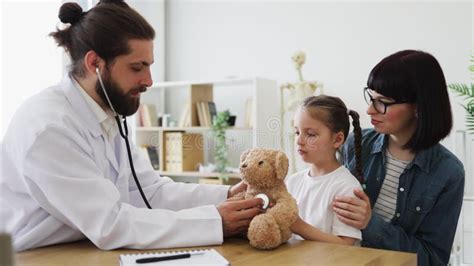 Doctor Demonstrates Medical Examination With Teddy Bear In Clinic Stock