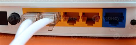 The Internet Cable Plugs Are Connected To The Internet Router Which Lies On A Bright Orange