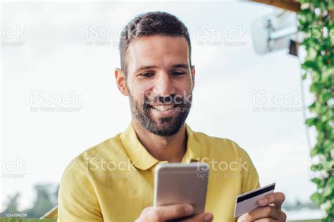젊은 남자가 그의 손에 휴대 전화와 신용 카드를 들고 웃 고 남자에 대한 스톡 사진 및 기타 이미지 남자 미소 성인