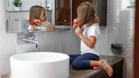 Premium Photo Girl Combing Hair While Looking In Mirror