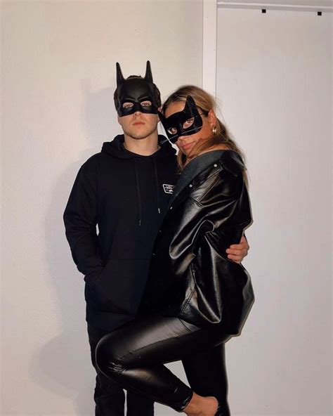 Two People Dressed Up As Batman And Catwoman Standing Next To Each