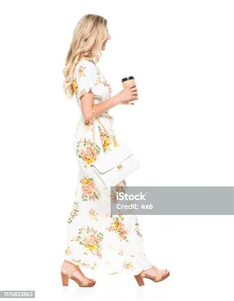 사이드 뷰 프로필 보기 전체 길이 2029 세 성인 금발 머리 긴 머리 백인 젊은 여성 앞을 걷고 흰색 배경 착용 드레스 긴 드레스 웃고 쾌활 하 고 커피 컵 지갑을 들고