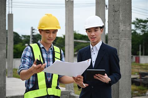 감독과 프로젝트 관리자가 현장에서 건설 계획을 검토합니다 감독은 무전기를 사용하여 업데이트를 하고 관리자는 태블릿을 참조하여 세부 사항을 확인합니다 2명에 대한 스톡 사진