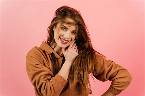 라이프 스타일 영감을 받고 행복한 여성은 분홍색 배경에서 미소짓고 웃고 얼굴을 찡그린다 사진 스튜디오에서 포즈를 취하는 모델 소녀 착용 갈색 오버 사이즈 의상 25 29세에