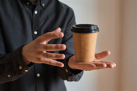 남자는 커피 나 차와 함께 손 종이 컵에 들고 사업가가 커피를 마십니다 순간을 즐기고 휴식을 취하십시오 커피가서 일회용 종이 컵 카페에서 서비스를 가져 가라 뜨거운 맛있는