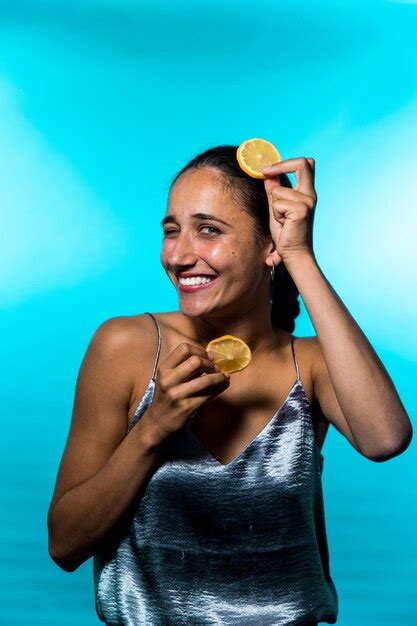 Premium Photo Portrait Of Smiling Woman Holding Lemon Against Blue