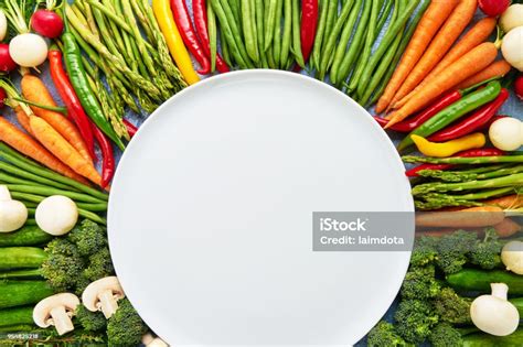 중간에 빈 흰색 접시와 야채 배경 당근 토마토 아스파라거스 브로콜리 고추 후추 녹색 콩 보기 상위 공간을 복사 합니다 유기