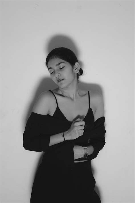 Dl 가슴에 손 갈색 머리 검정 드레스 고립 된 배경 고요한 표정 눈을 감다 델리 드레스 명상 적 미니멀리스트 미묘한 그림자 부드러운 조명 블랙 앤