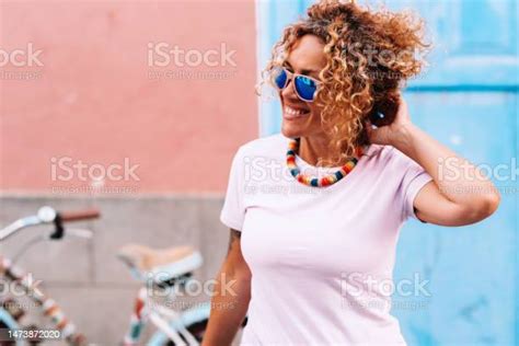 웃고 집 밖에서 야외 레저 활동을 즐기는 쾌활한 젊은 여성의 초상화 자전거는 배경과 집에 주차되어 있습니다 마을의 건강한 활동적인 라이프 스타일 사람들 미녀 숙녀 재미