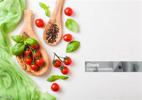 Oilve 나무 접시에 바 질와 함께 포도 나무와 흰색 부엌 배경에 후추와 숟가락에 유기농 체리 Sugardrop 토마토