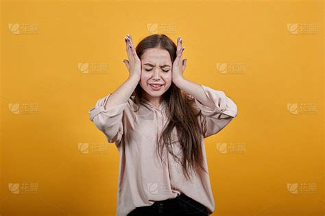 穿着时尚淡色衬衫的白人妇女双手放在头上，头痛