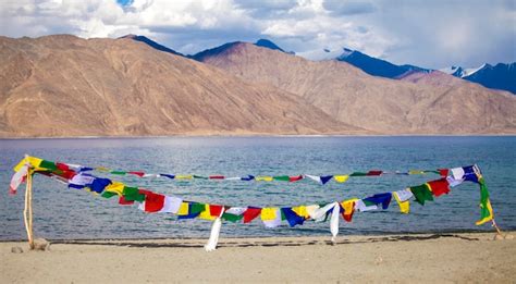 Premium Photo Multi Colored Prayer Flags Waving On Lakeshore Against