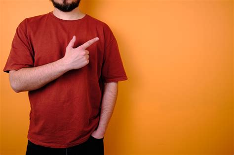 빨간색 티셔츠와 청바지를 입고 주황색 벽 근처에서 포즈를 취하는 남성 모델 손 제스처와 감정 스튜디오 사진 감정 힘과 재미의 개념 비문에 대한 장소 T 셔츠에 대한 스톡