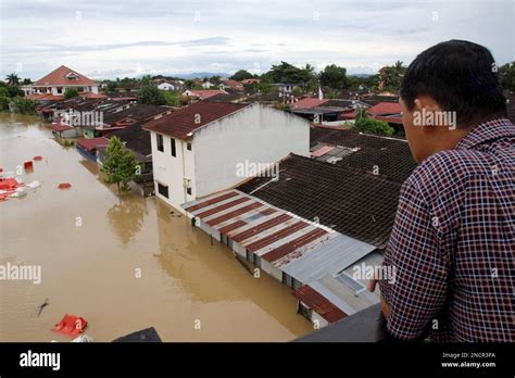 A Resident Looks Out At A Town Submerged By Flood Waters In Alor Setar